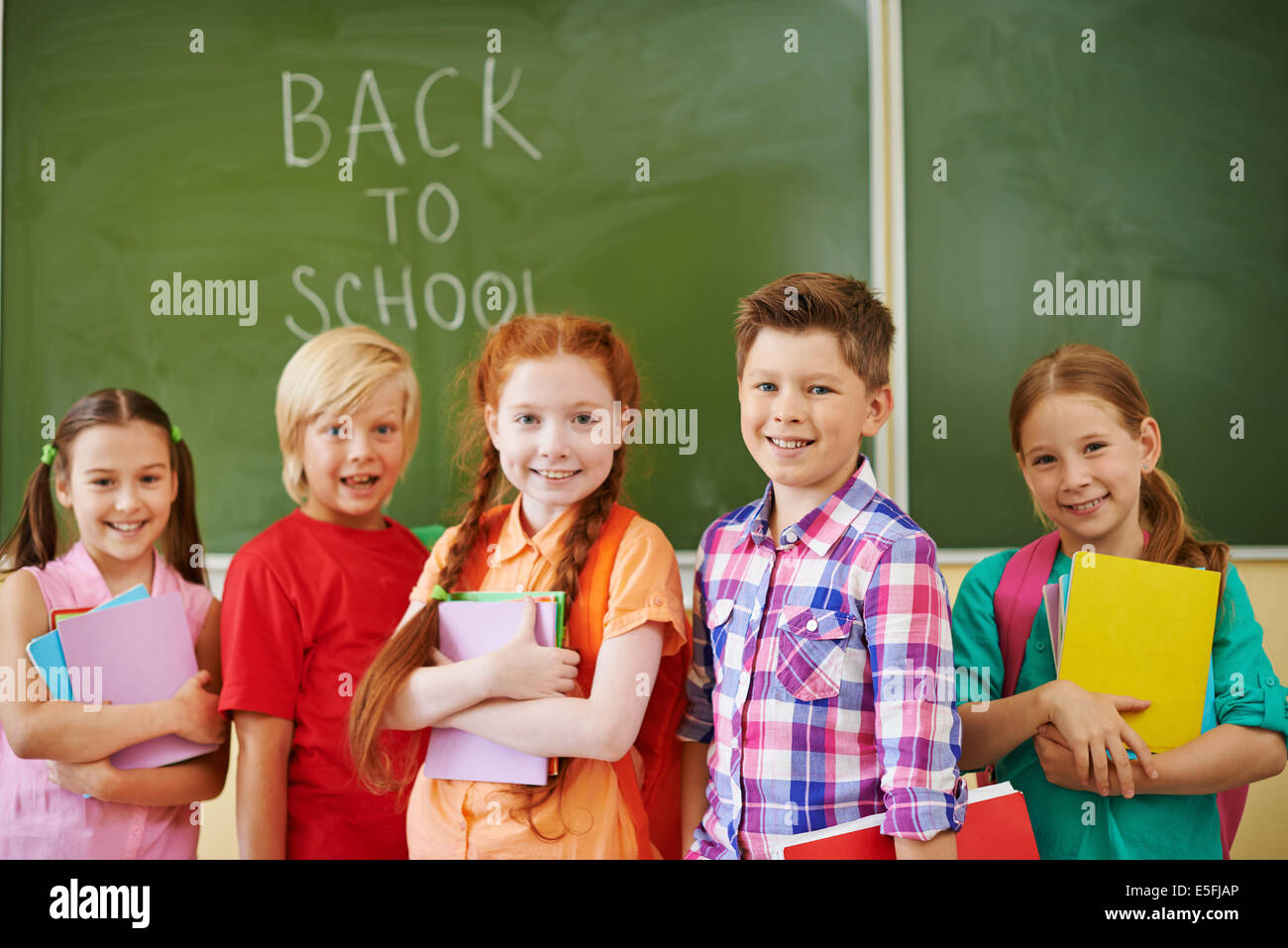 Portrait of friendly classmates with books looking at camera on ...