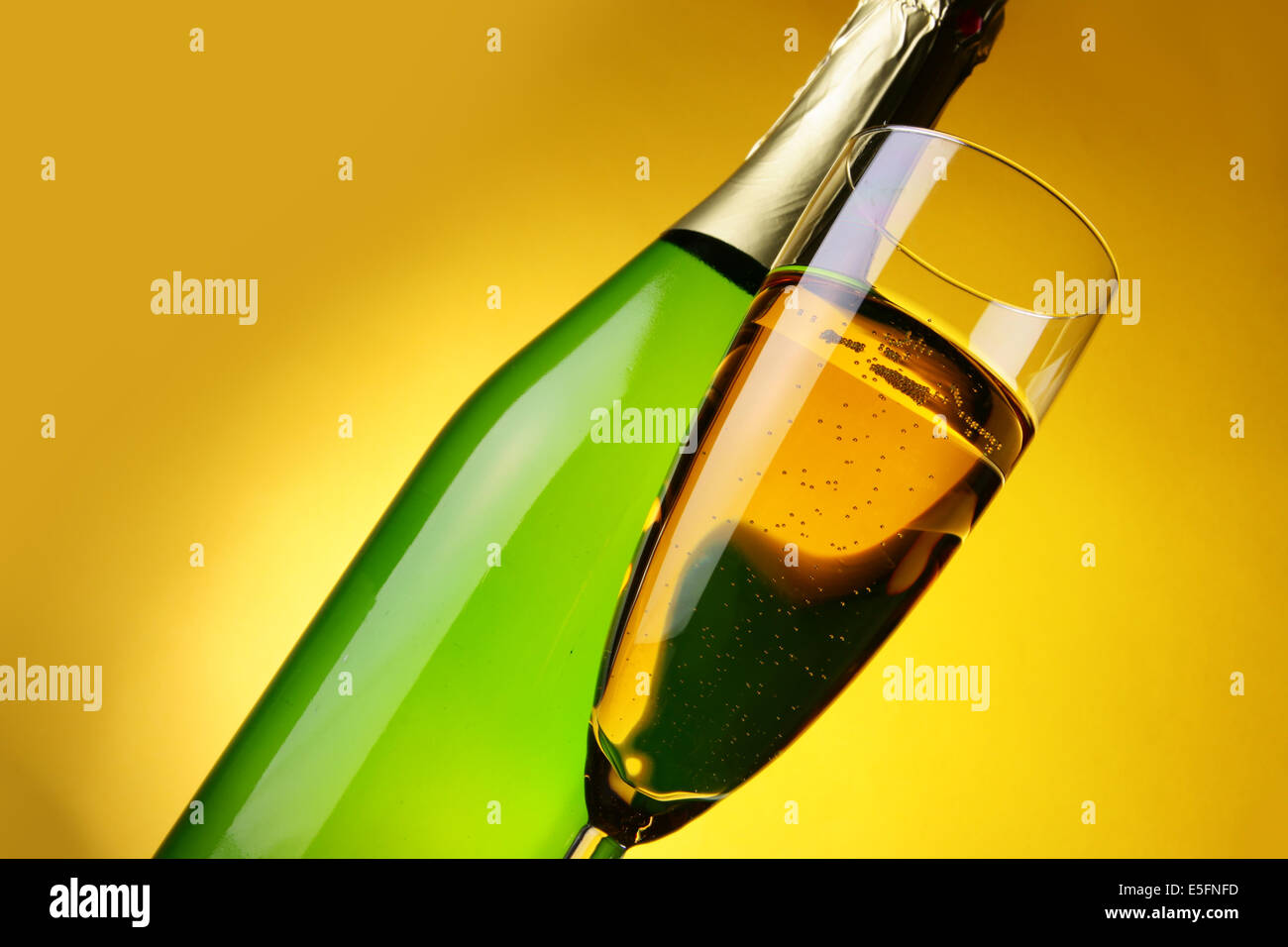 Bottle and glass of champagne close-up over yellow background Stock ...