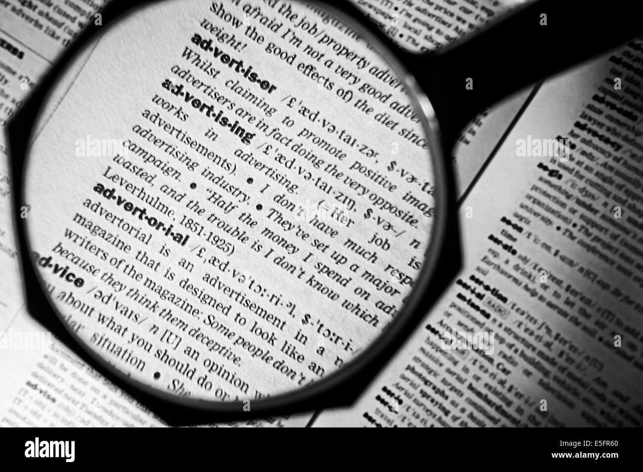 Magnifying glass on the advertising in dictionary. Selective focus on ...