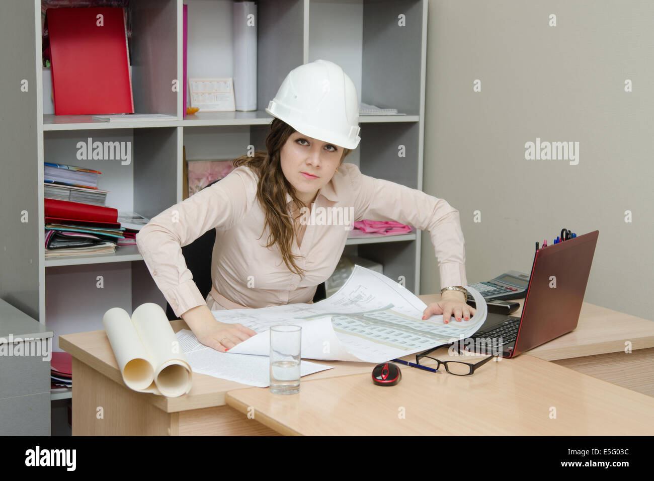 A young girl in a helmet works at his desk in the office Stock Photo ...