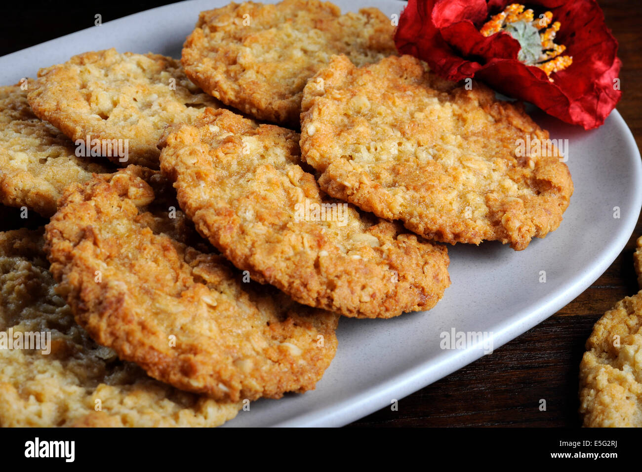 Traditional Anzac biscuits on dark recycled wood with remembrance red ...