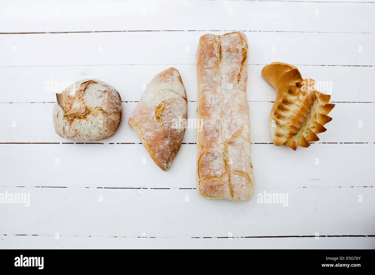 Loafs of bread with different shapes on a white wood table Stock Photo ...