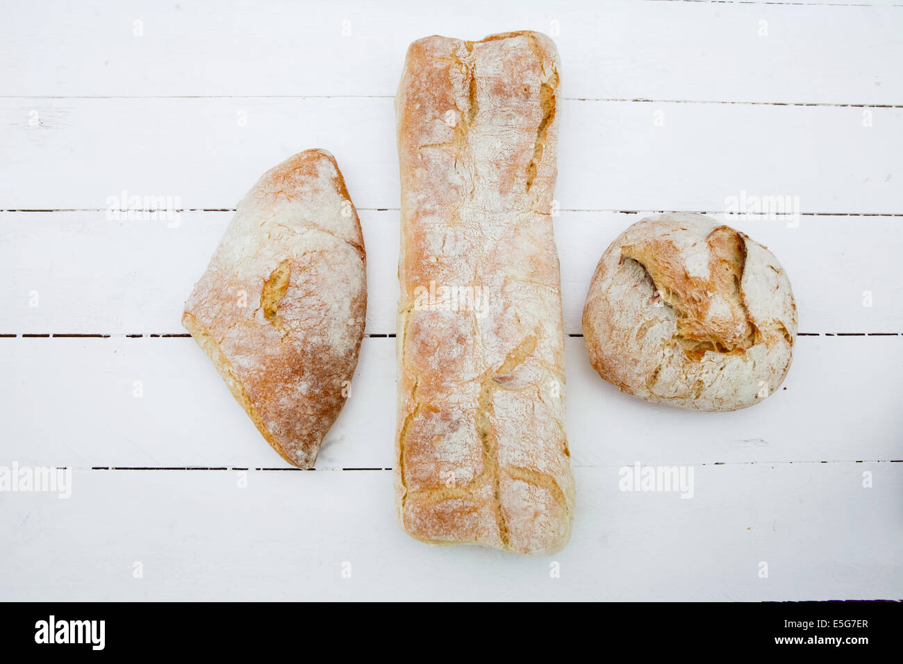 Loafs of bread with different shapes on a white wood table Stock Photo ...