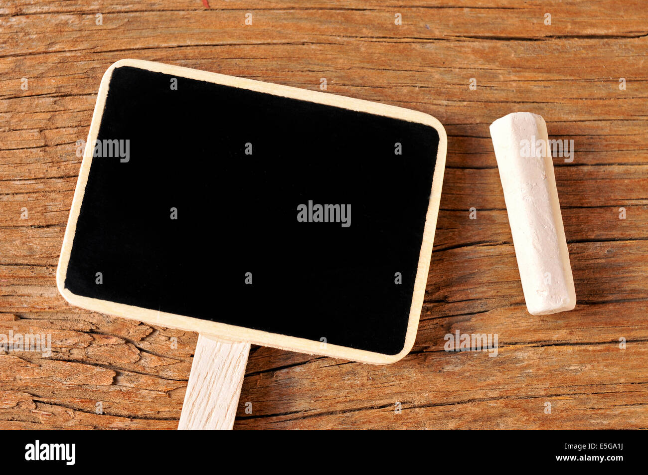 a blank chalkboard label and a piece chalk on a rustic wooden ...