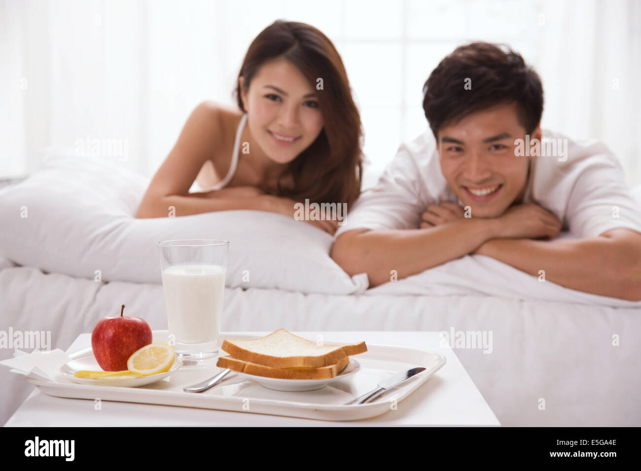 Young couple lying prone on bed Stock Photo - Alamy