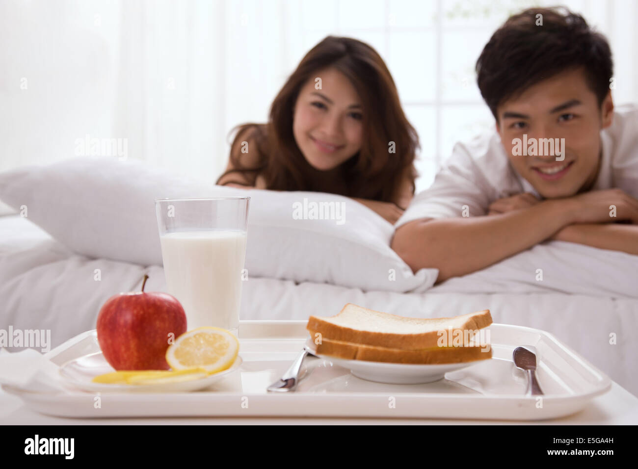 Young couple lying prone on bed Stock Photo - Alamy