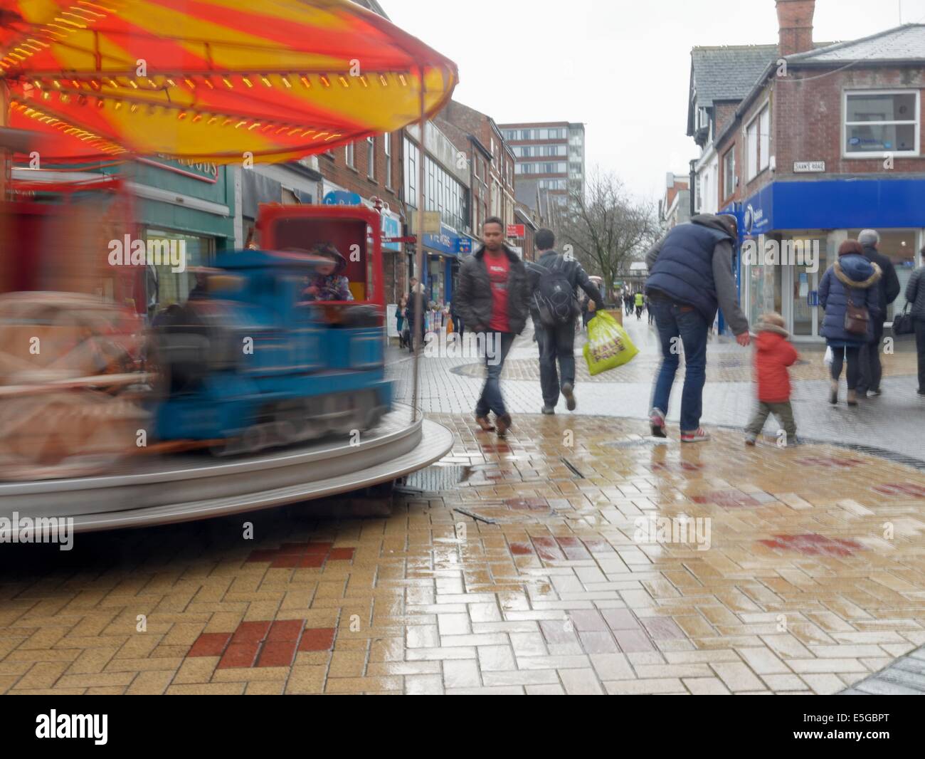A children's roundabout in the rain looking toward the Stamford Quarter ...