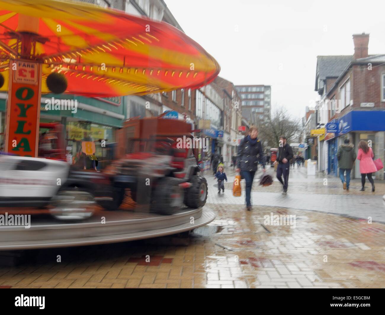 A children's roundabout in the rain looking toward the Stamford Quarter ...