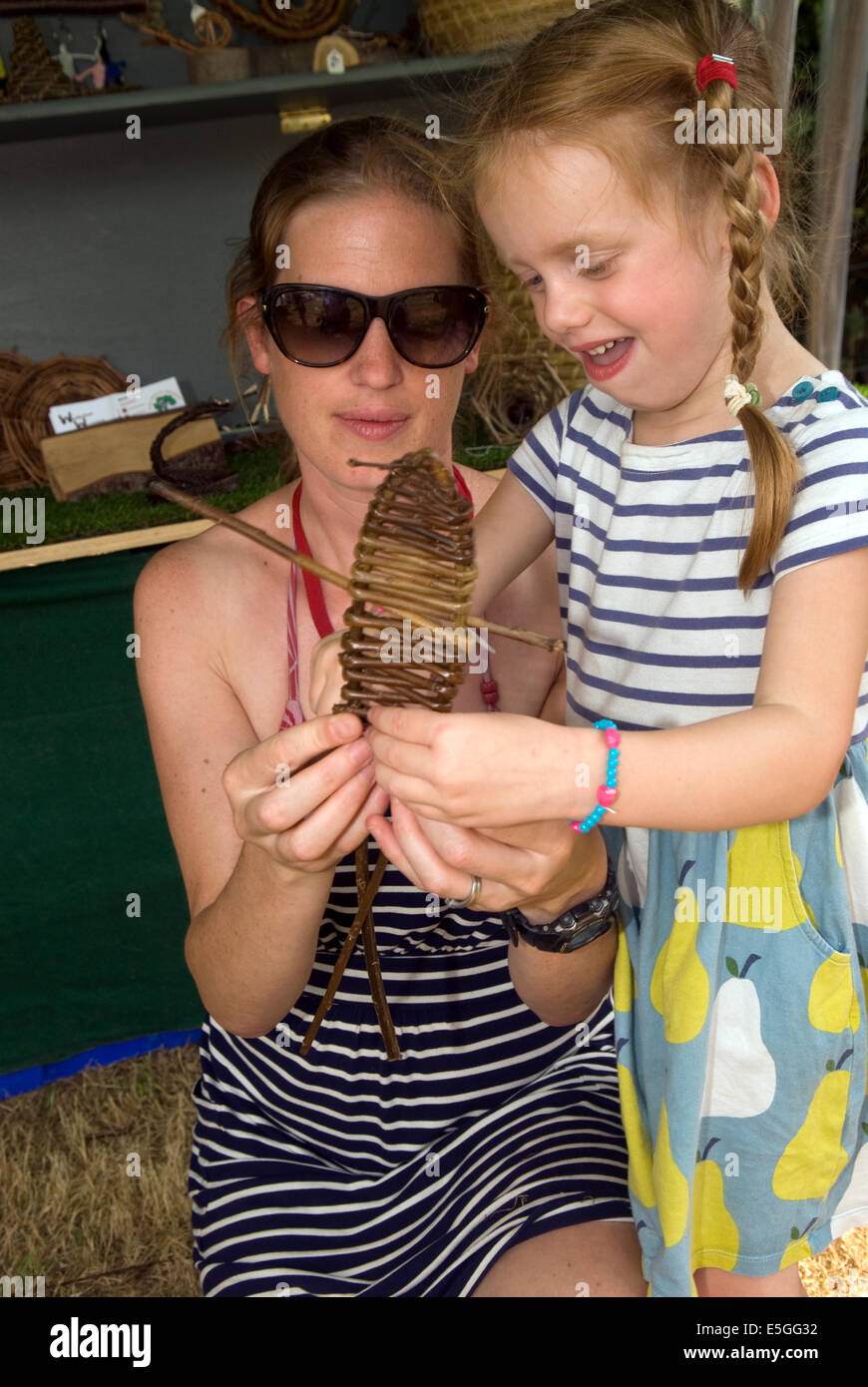 Mother with her 4 year old daughter weaving a willow fish at a country ...