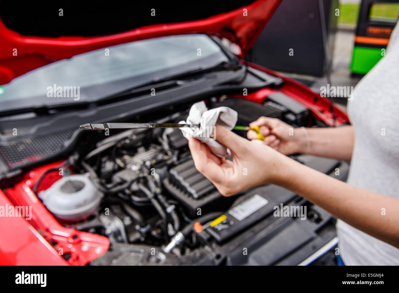 A young woman measuring the oil level of a car. Photo: picture alliance ...