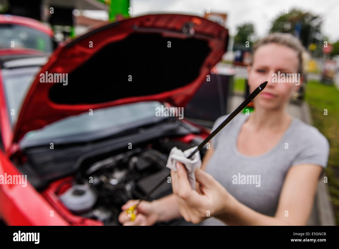 A young woman measuring the oil level of a car. Photo: picture alliance ...