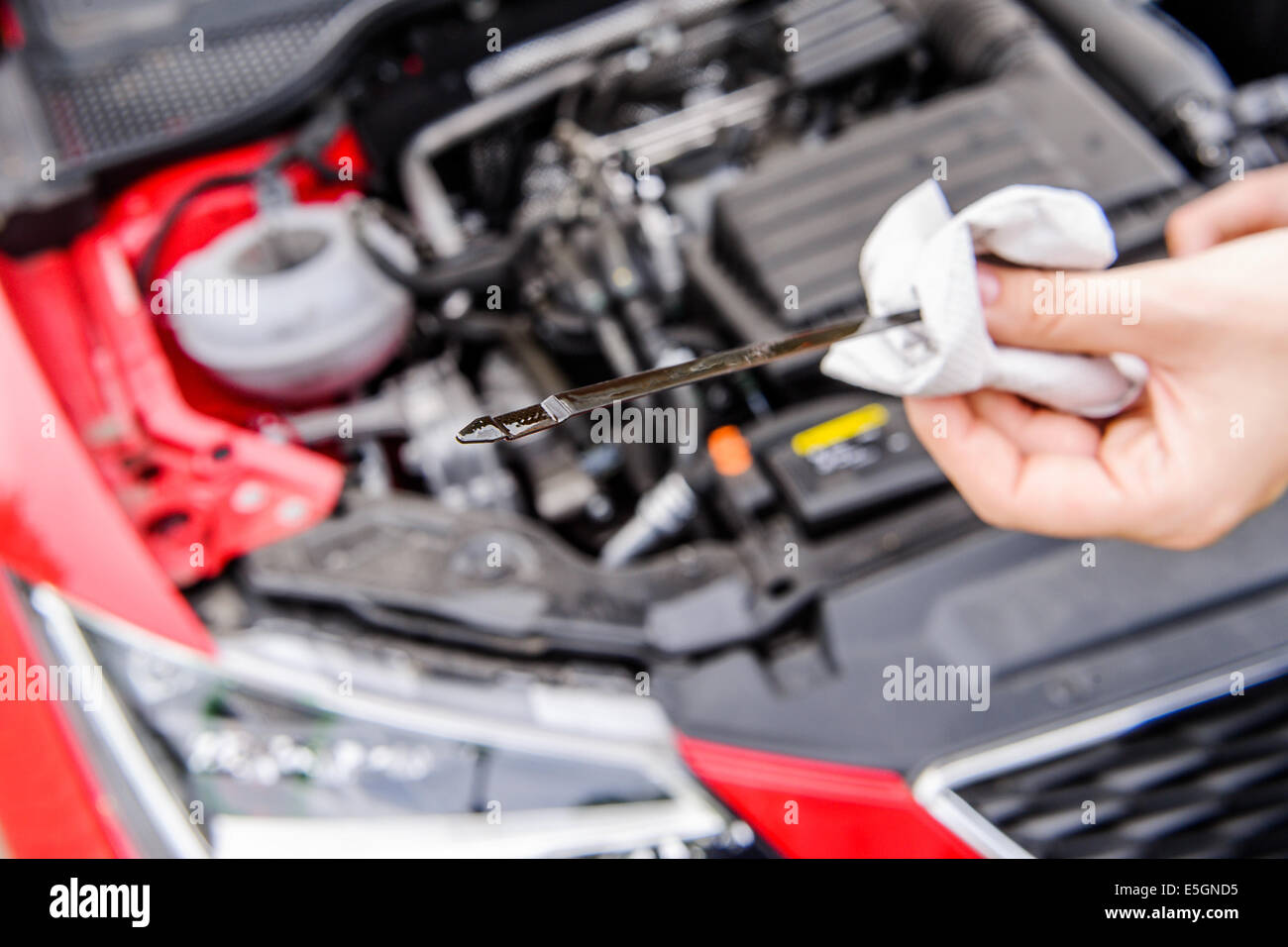 A young woman measuring the oil level of a car. Photo: picture alliance ...