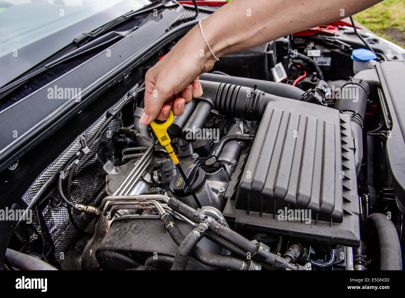 A young woman measuring the oil level of a car. Photo: picture alliance ...