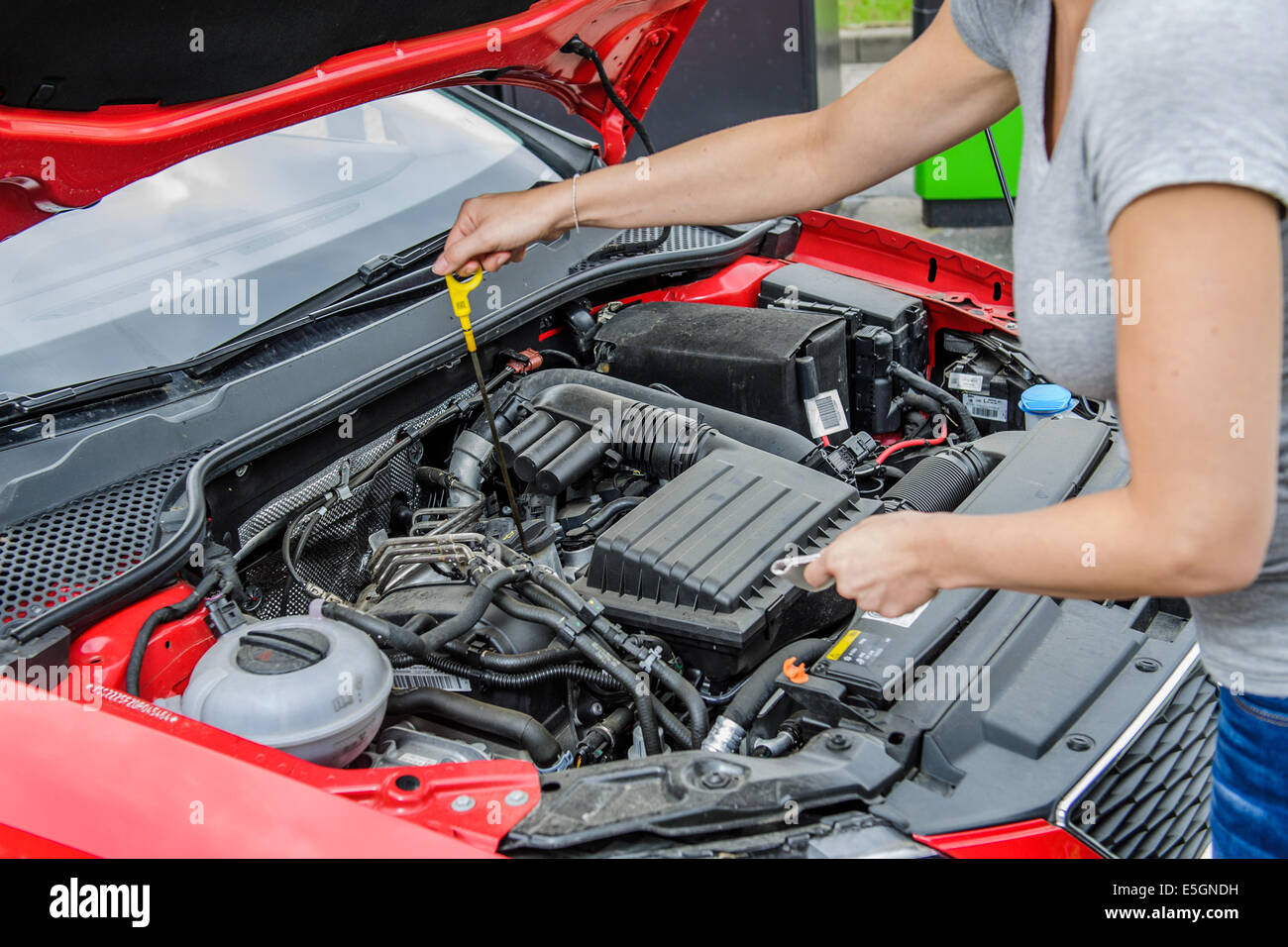 A young woman measuring the oil level of a car. Photo: picture alliance ...
