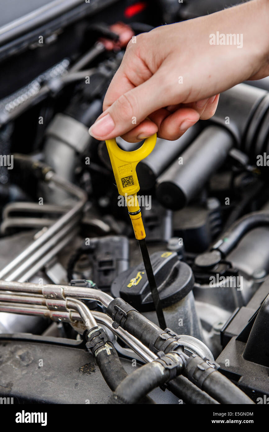 A young woman measuring the oil level of a car. Photo: picture alliance ...