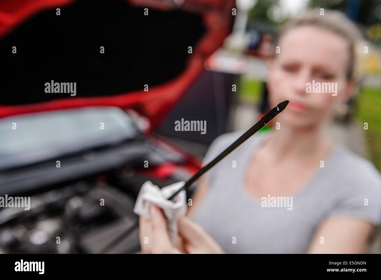 A young woman measuring the oil level of a car. Photo: picture alliance ...