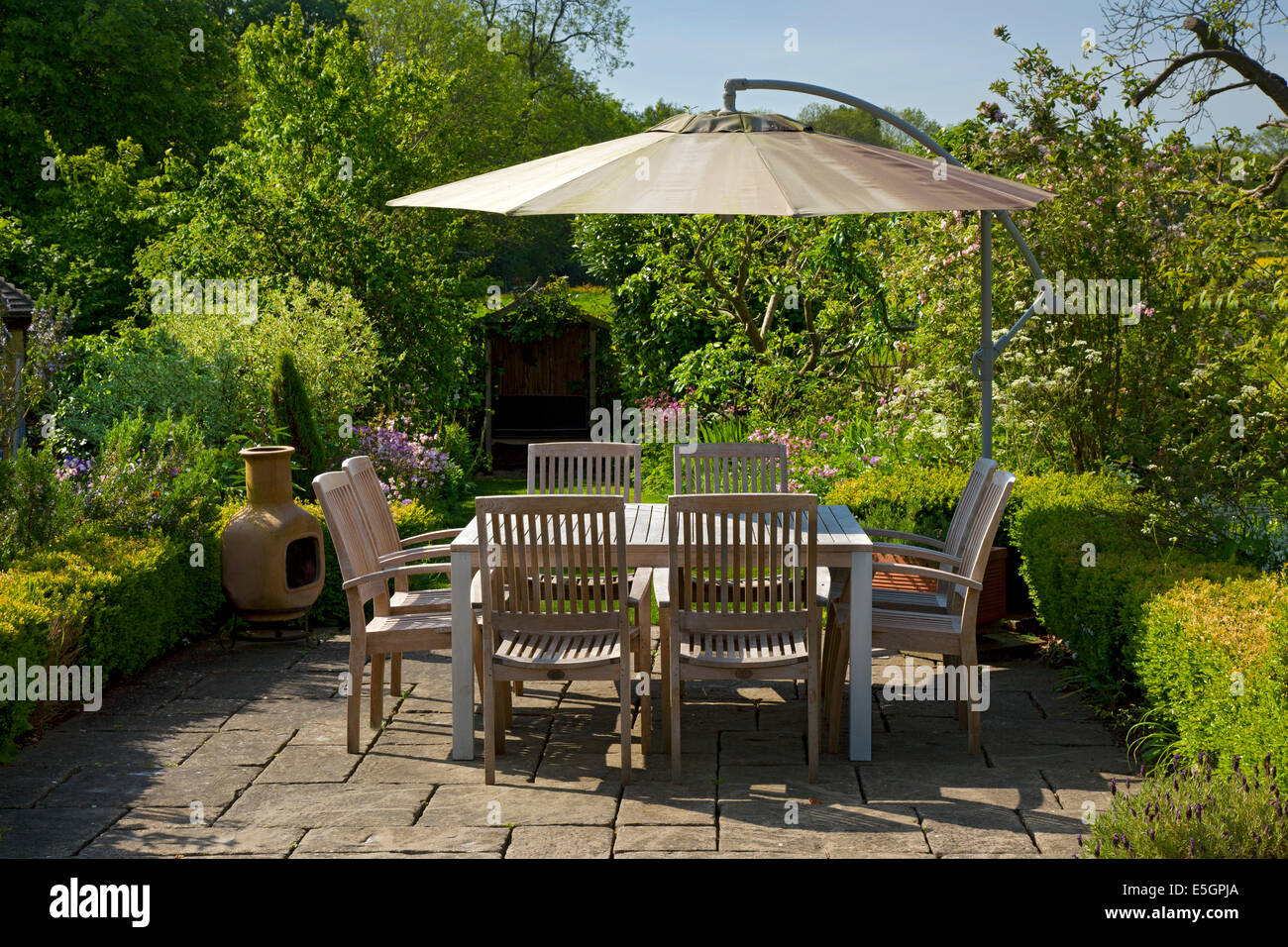 Outdoor eating area with table and chairs in English summer garden ...