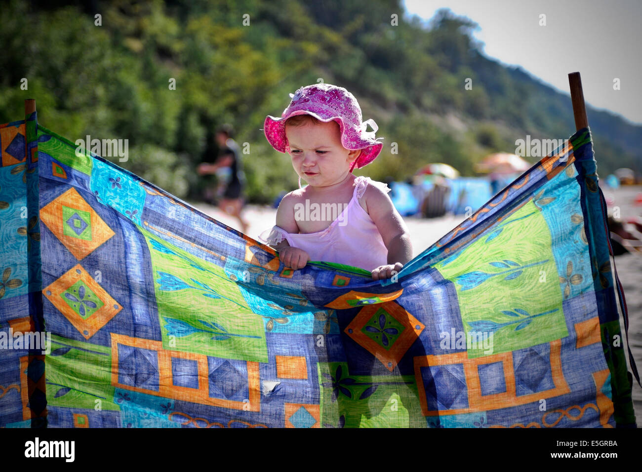 Little girl at the beach hiding behind a colorful screen Stock Photo ...