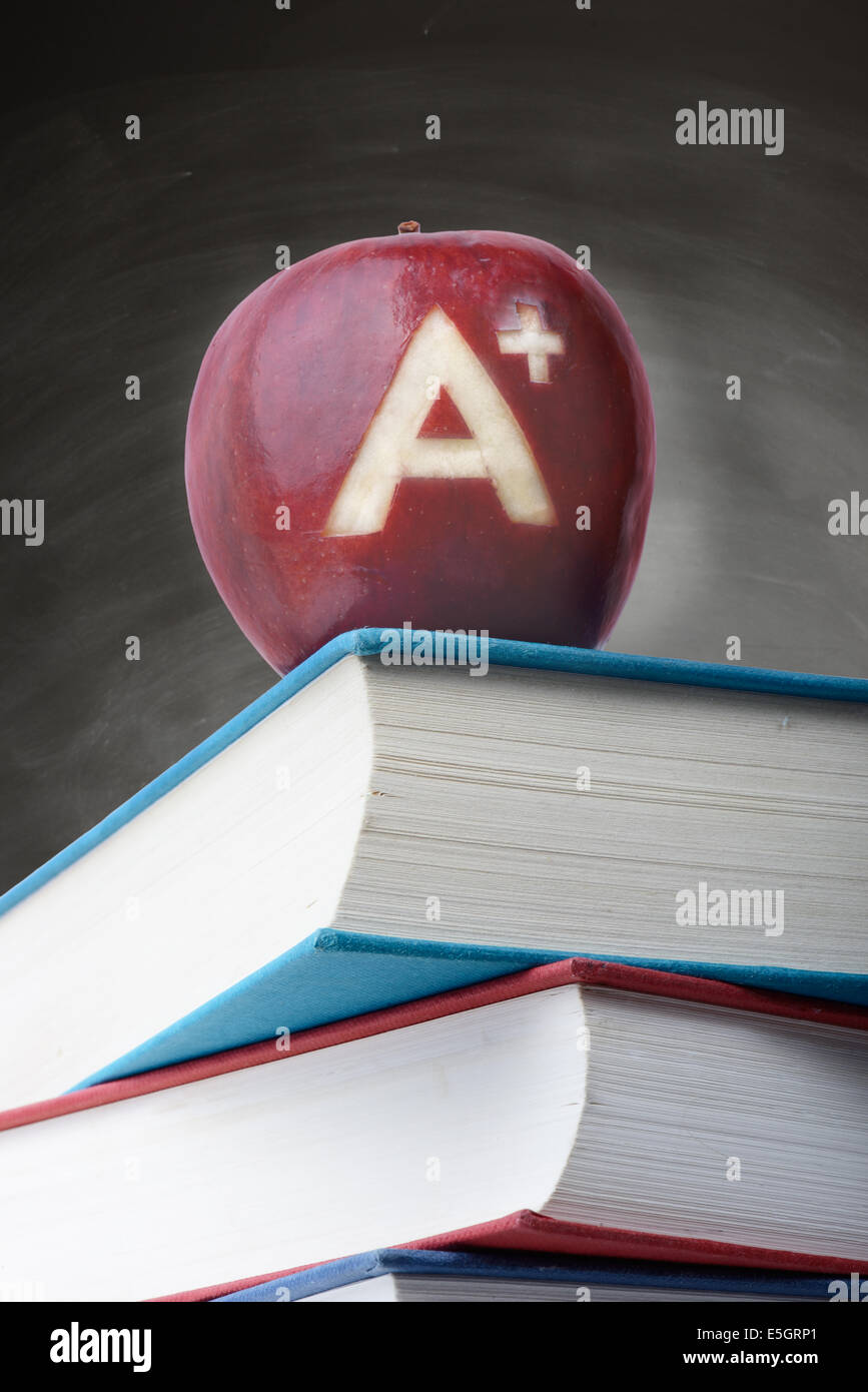 a red apple with an A plus carved on it upon a stack of books, concept ...