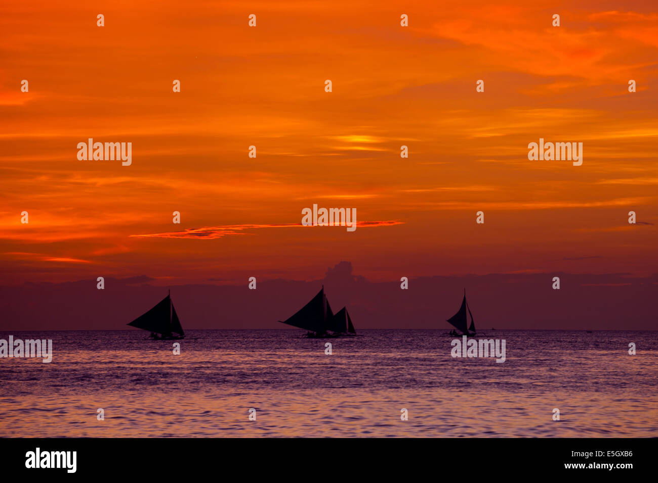 Sunset on tropical beach with sailing boats Stock Photo - Alamy