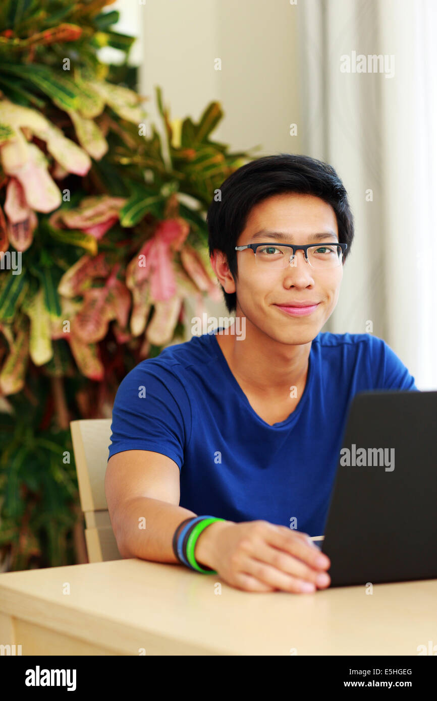Happy asian man sitting at the table with laptop at home Stock Photo - Alamy