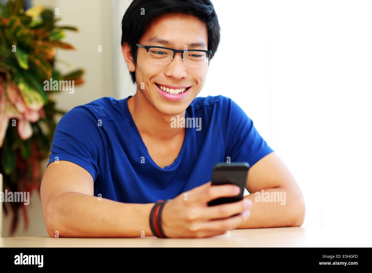 Happy asian man using smartphone at home Stock Photo - Alamy