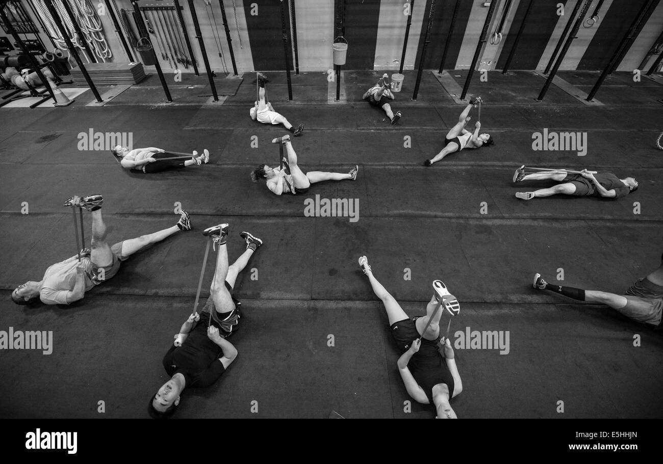 A group of people stretch before performing the workout of the day at ...