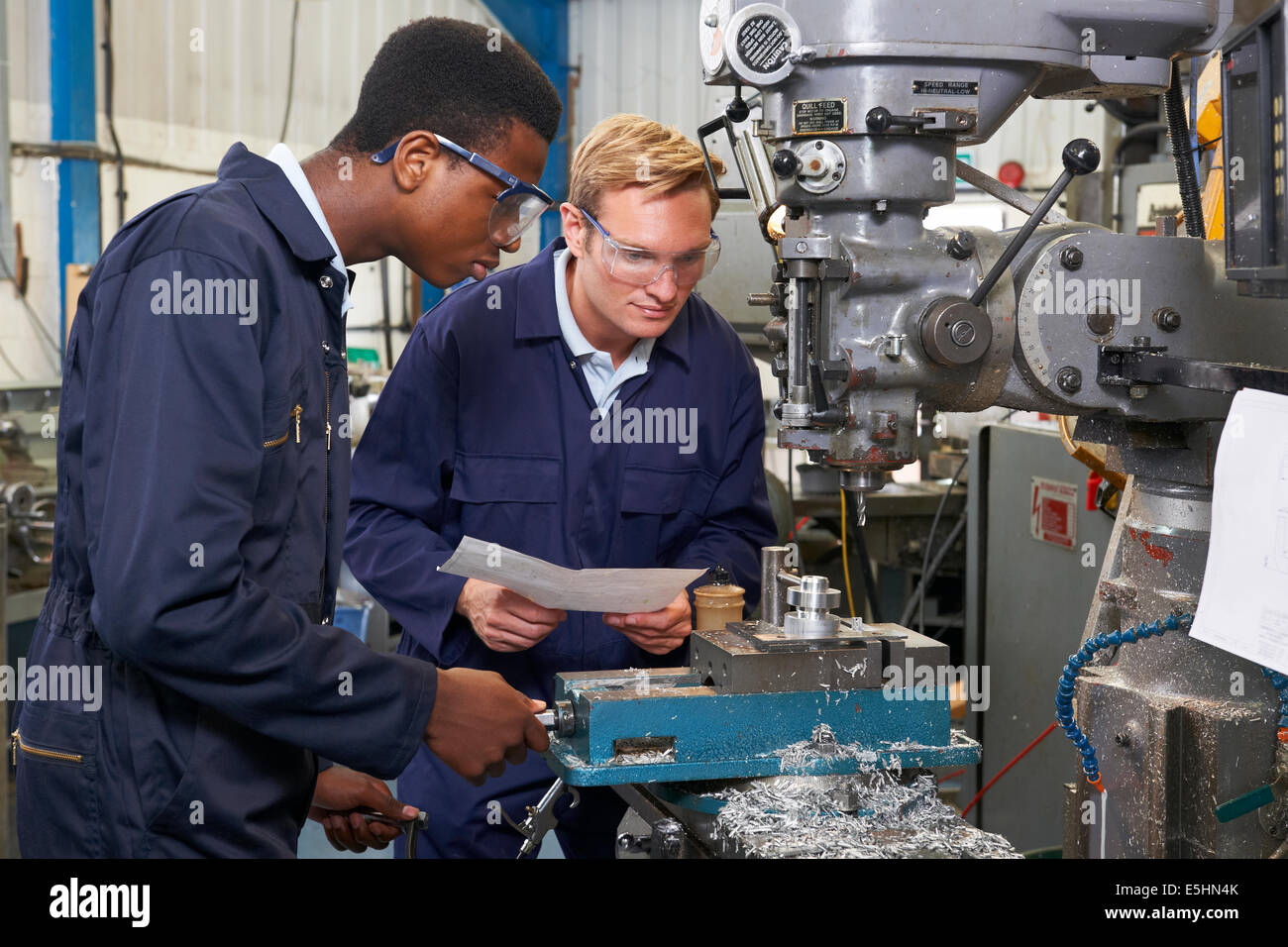 Engineer Showing Apprentice How to Use Drill In Factory Stock Photo - Alamy