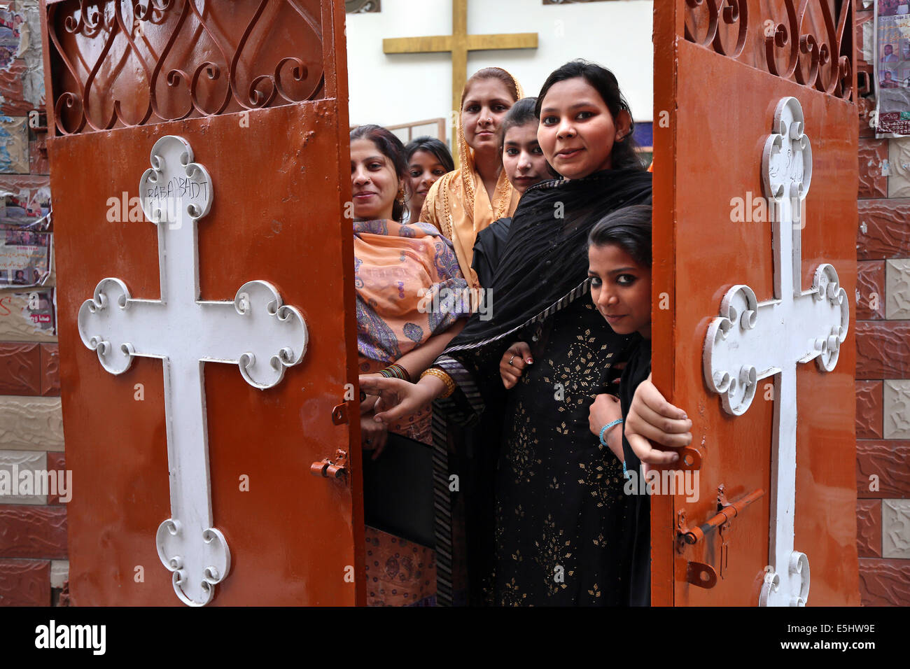 Christian women behind an iron gate with cross on the church compound ...