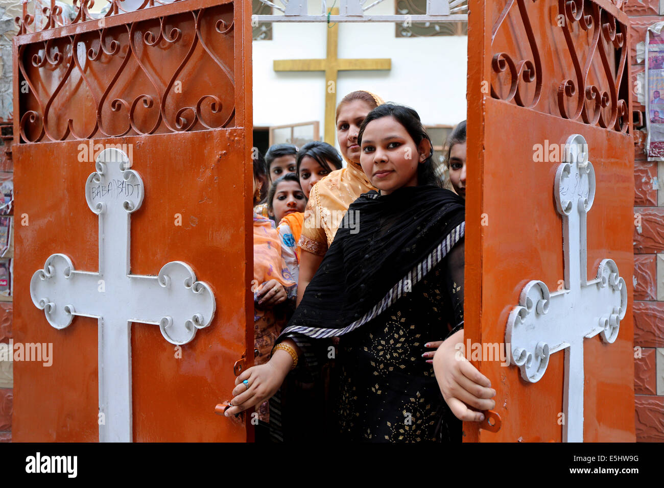 Christian women behind an iron gate with cross on the church compound ...