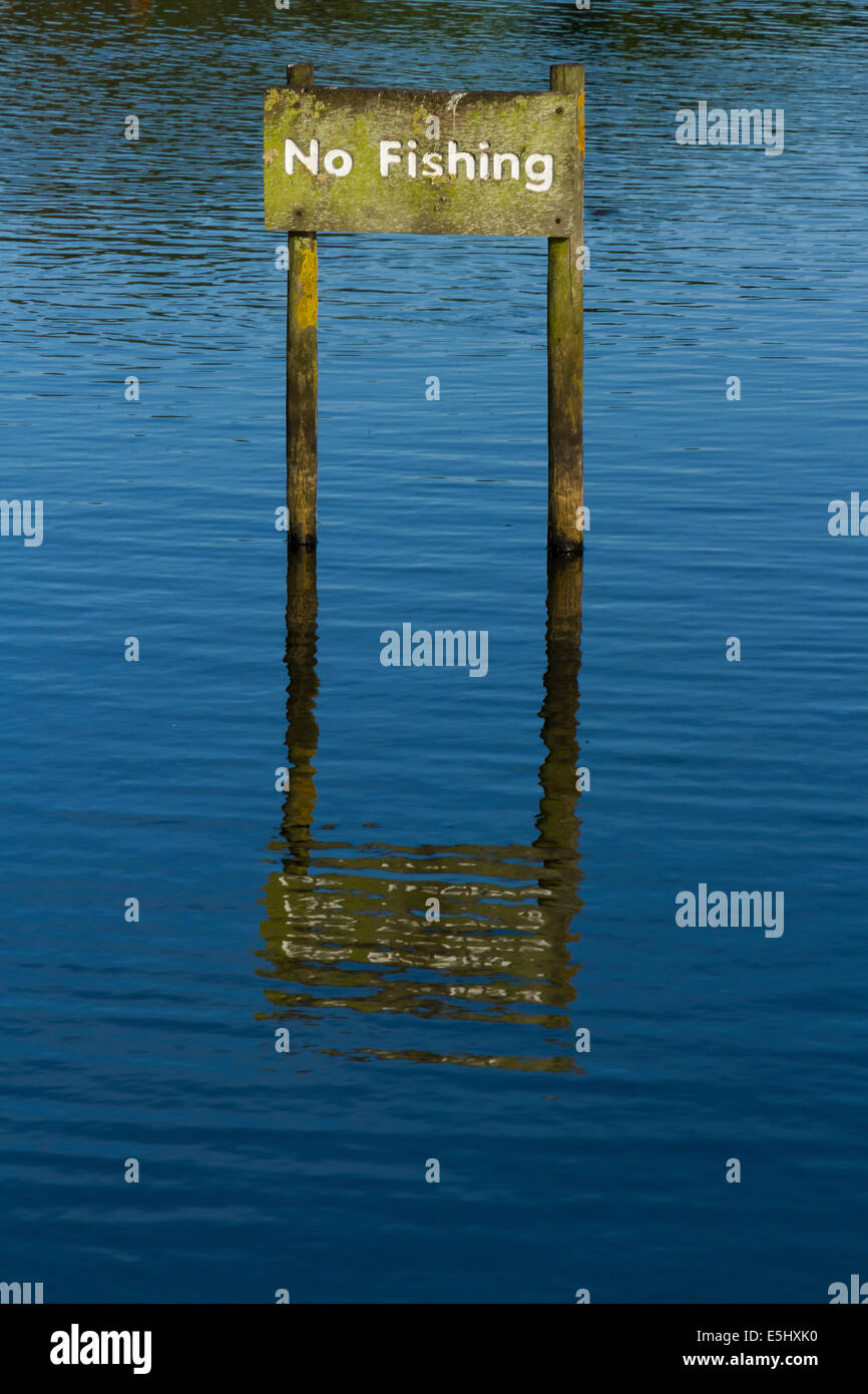 No Fishing sign in a lake, its reflection showing Stock Photo - Alamy