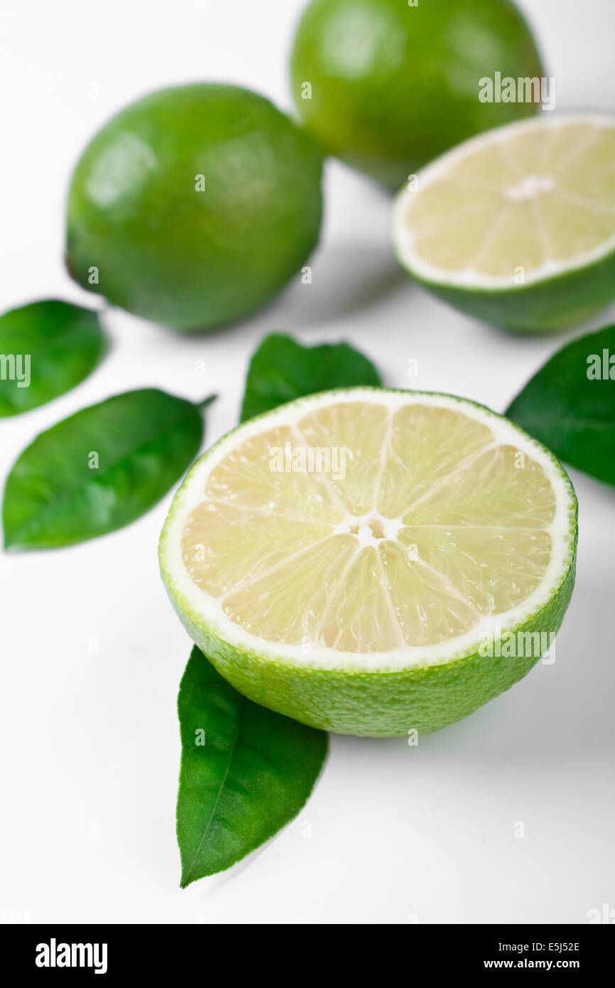 close up of a group of limes with leaves, one lime cut in half Stock ...