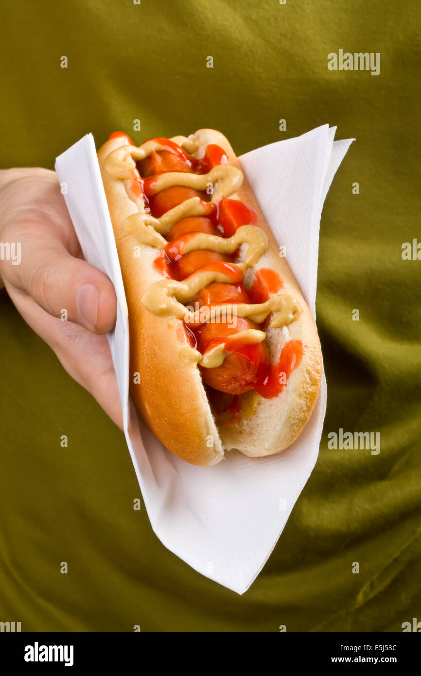 close up of a hot dog in a paper napkin being held in one hand Stock ...