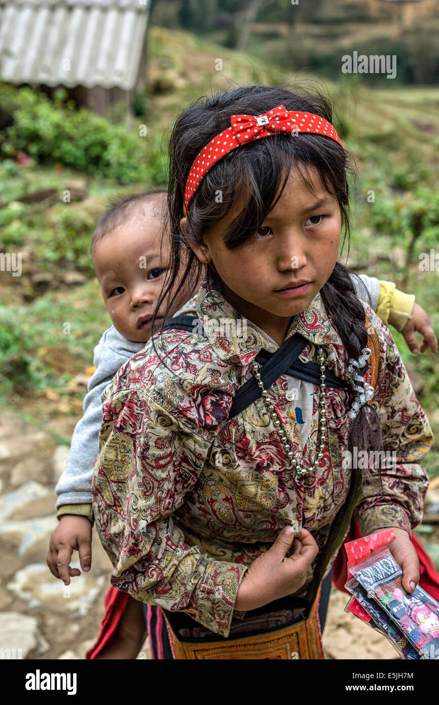 Young girl with baby on her back peddles Stock Photo - Alamy