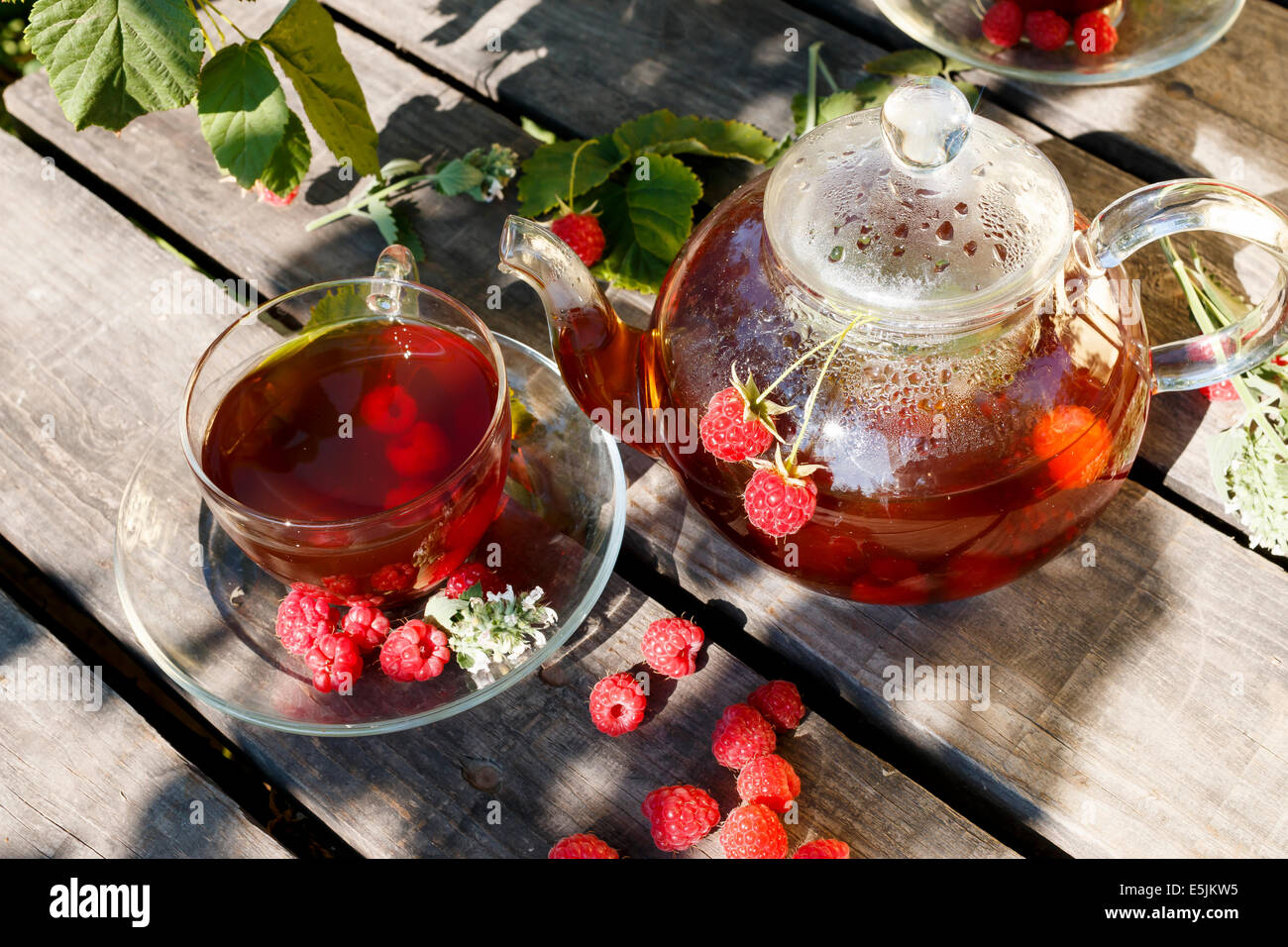 raspberry tea in transparent teapot and teacup on wooden table at ...