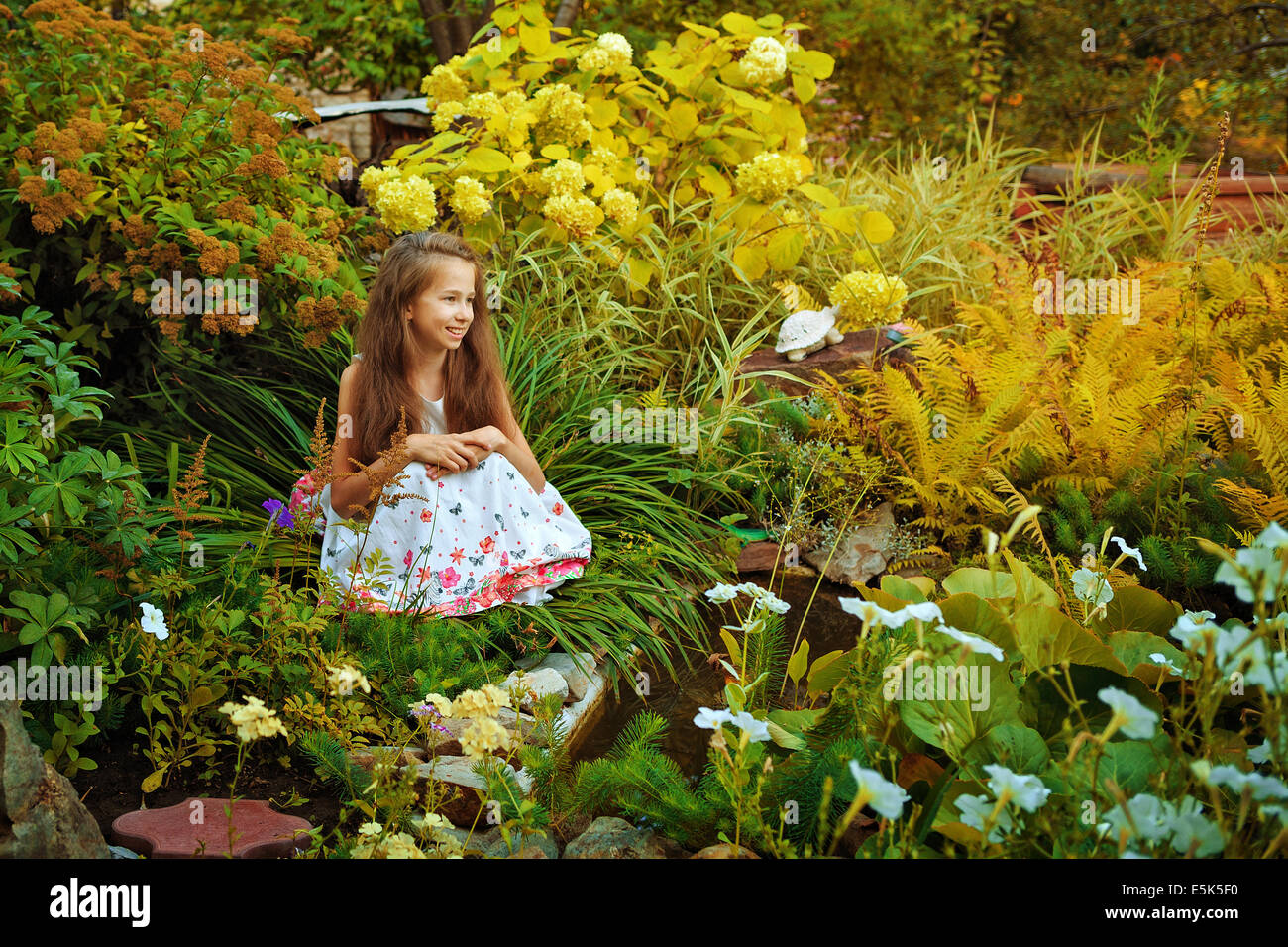 cute teen girl in the garden sat near an artificial pond Stock Photo ...