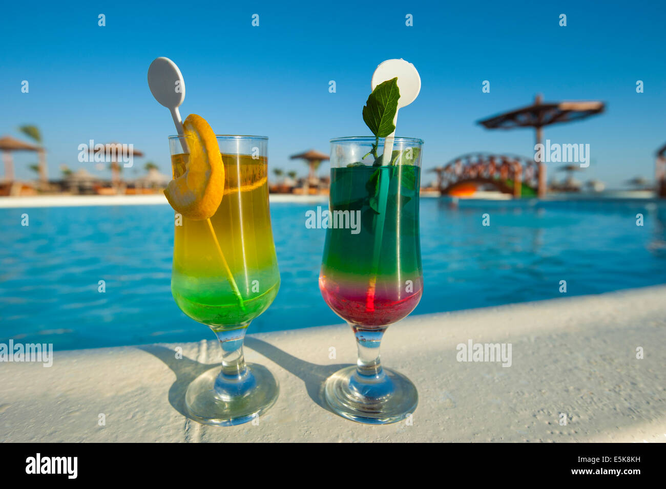 Two cocktail drinks on the side of a swimming pool in tropical summer ...