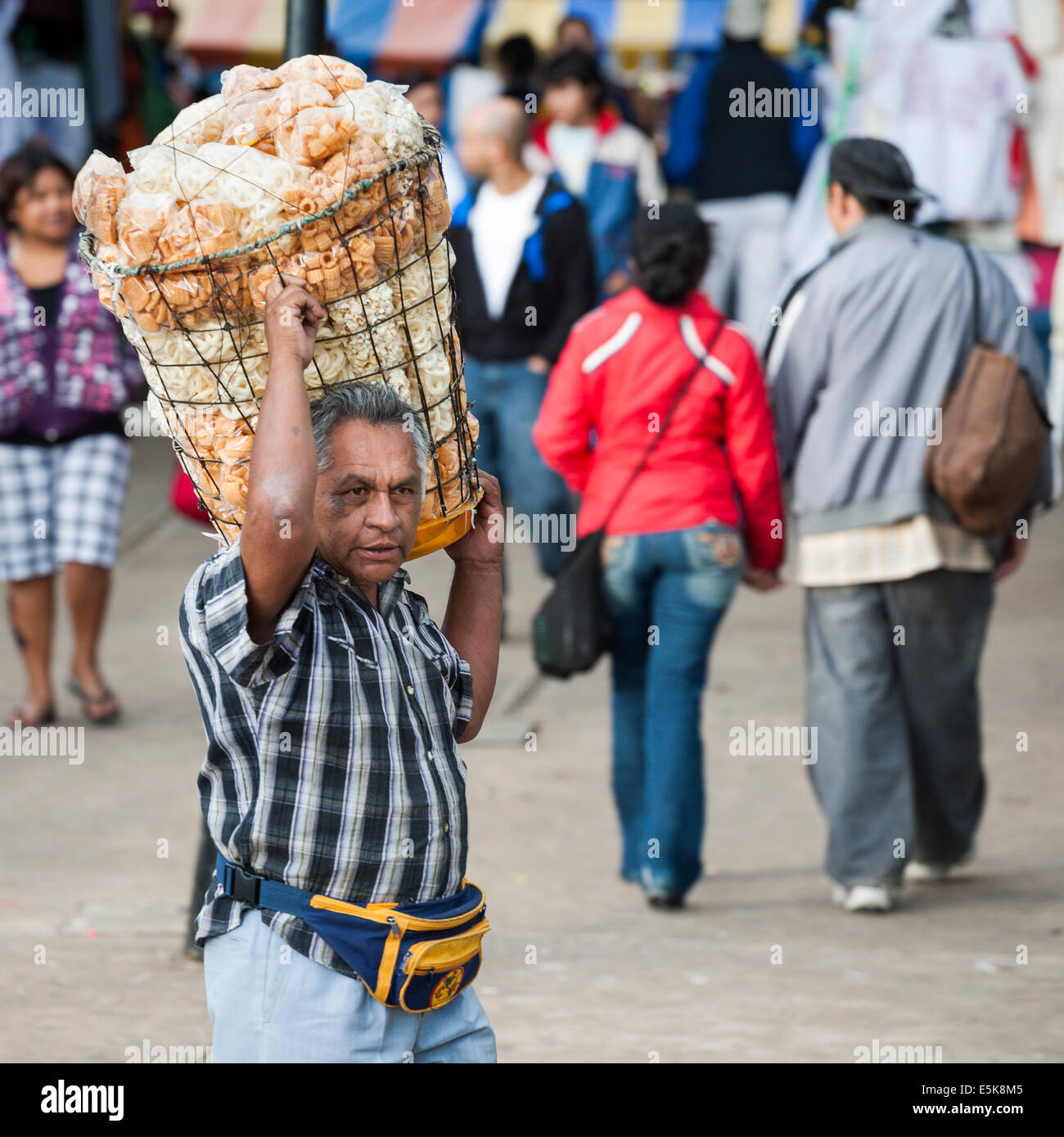 Snack Man. A street vendor with a money pouch hoists a huge bin of ...