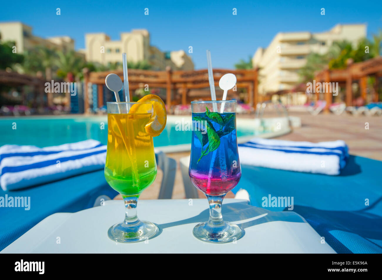 Two cocktail drinks on the side of a swimming pool in tropical summer ...