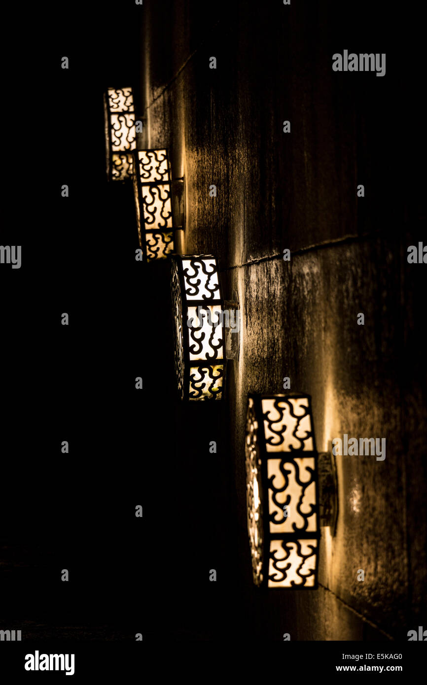 Four aligned decorative lights giving off reflections on a stone wall ...
