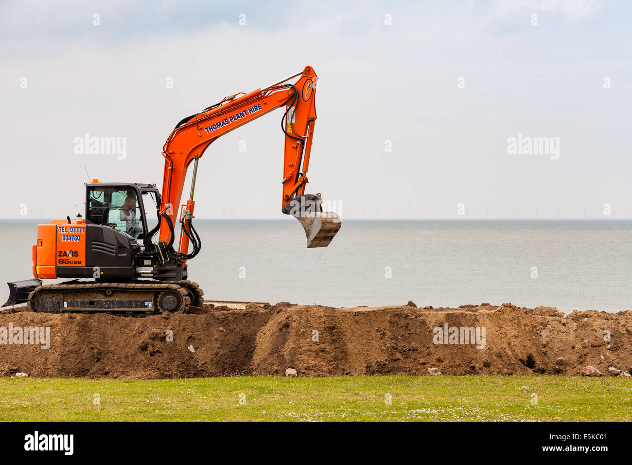 Digger operator working on Rhyl coastal shores, North Wales Stock Photo ...
