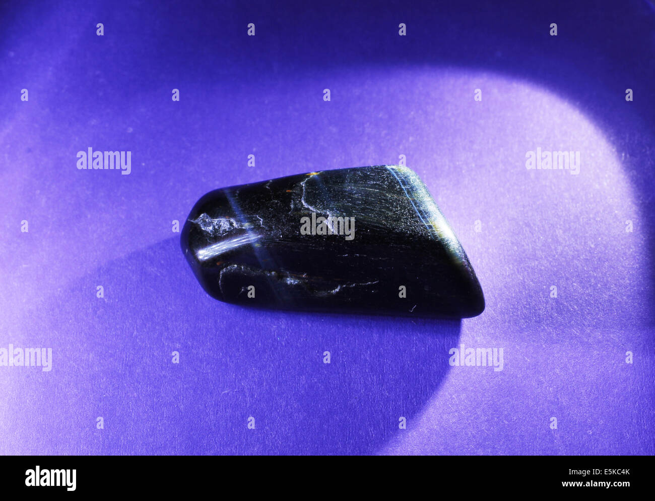 Hawk eye gem stone close up on purple background Stock Photo - Alamy