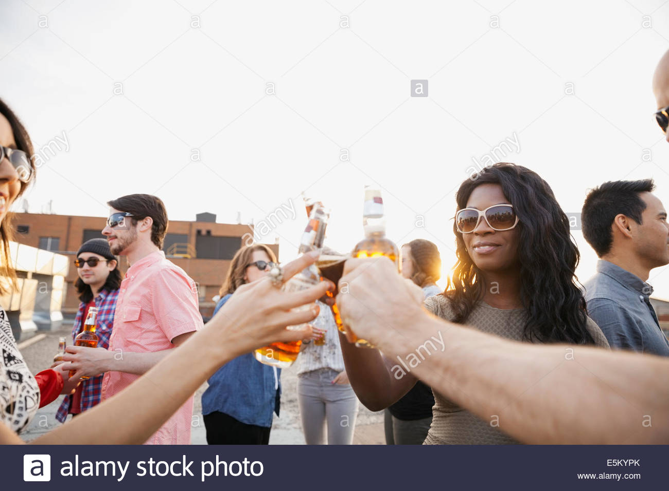 Friends toasting beer bottles at rooftop party Stock Photo - Alamy