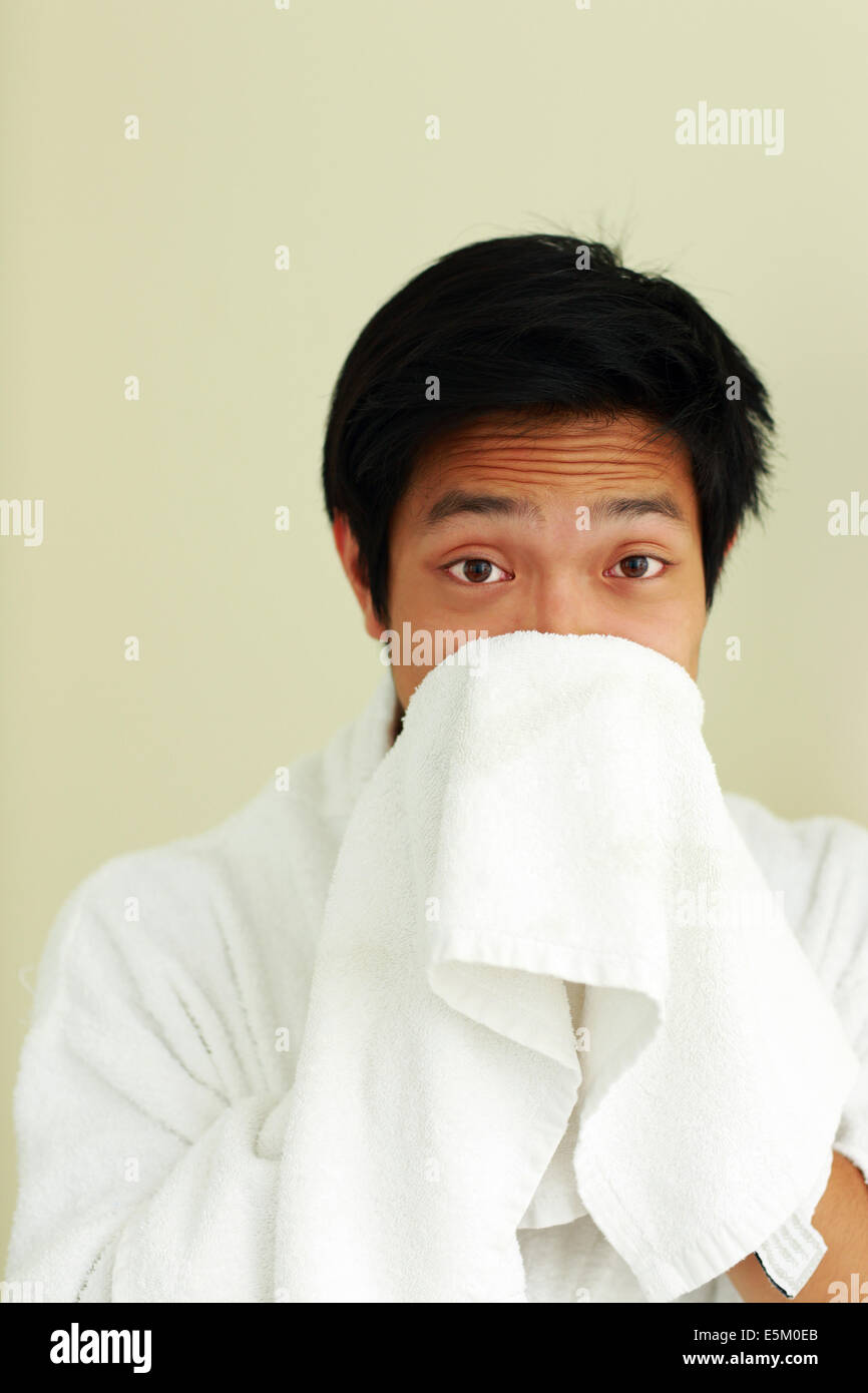 Young asian man in bathrobe wiping face with a towel Stock Photo - Alamy