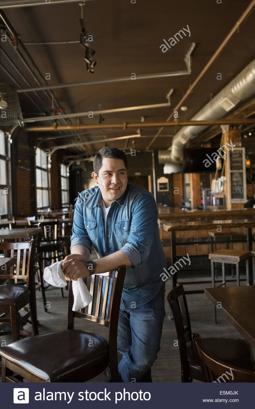 Smiling pub owner leaning on chair Stock Photo - Alamy