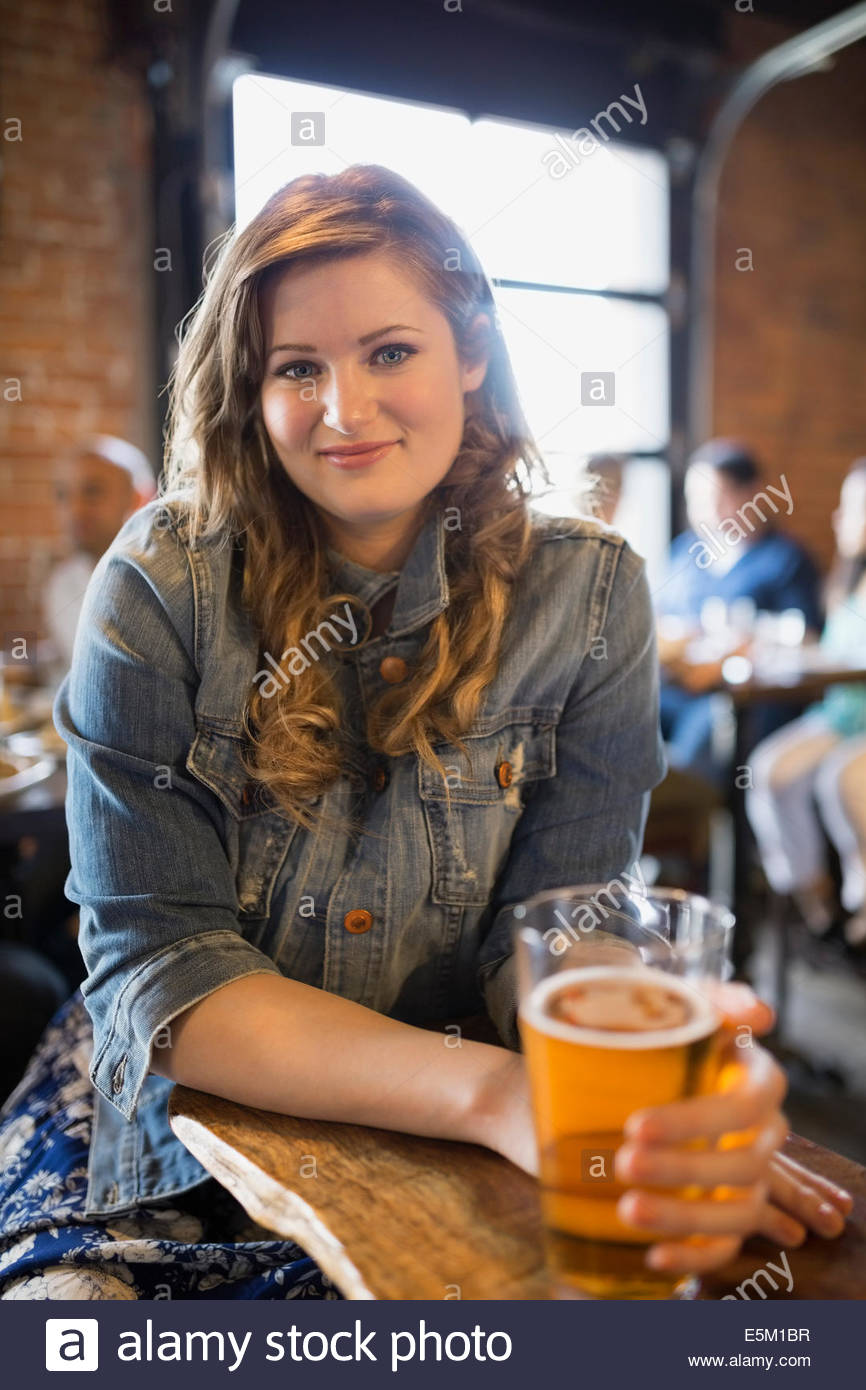 Portrait of smiling woman drinking beer in pub Stock Photo - Alamy