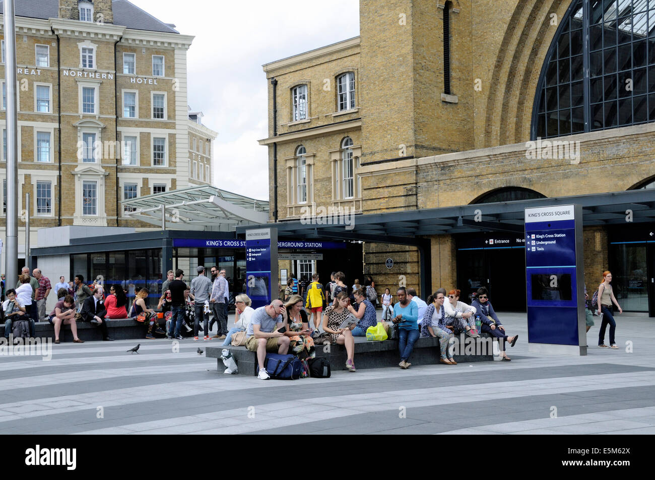 People sitting in Kings Cross Station Square, London England Britain UK ...