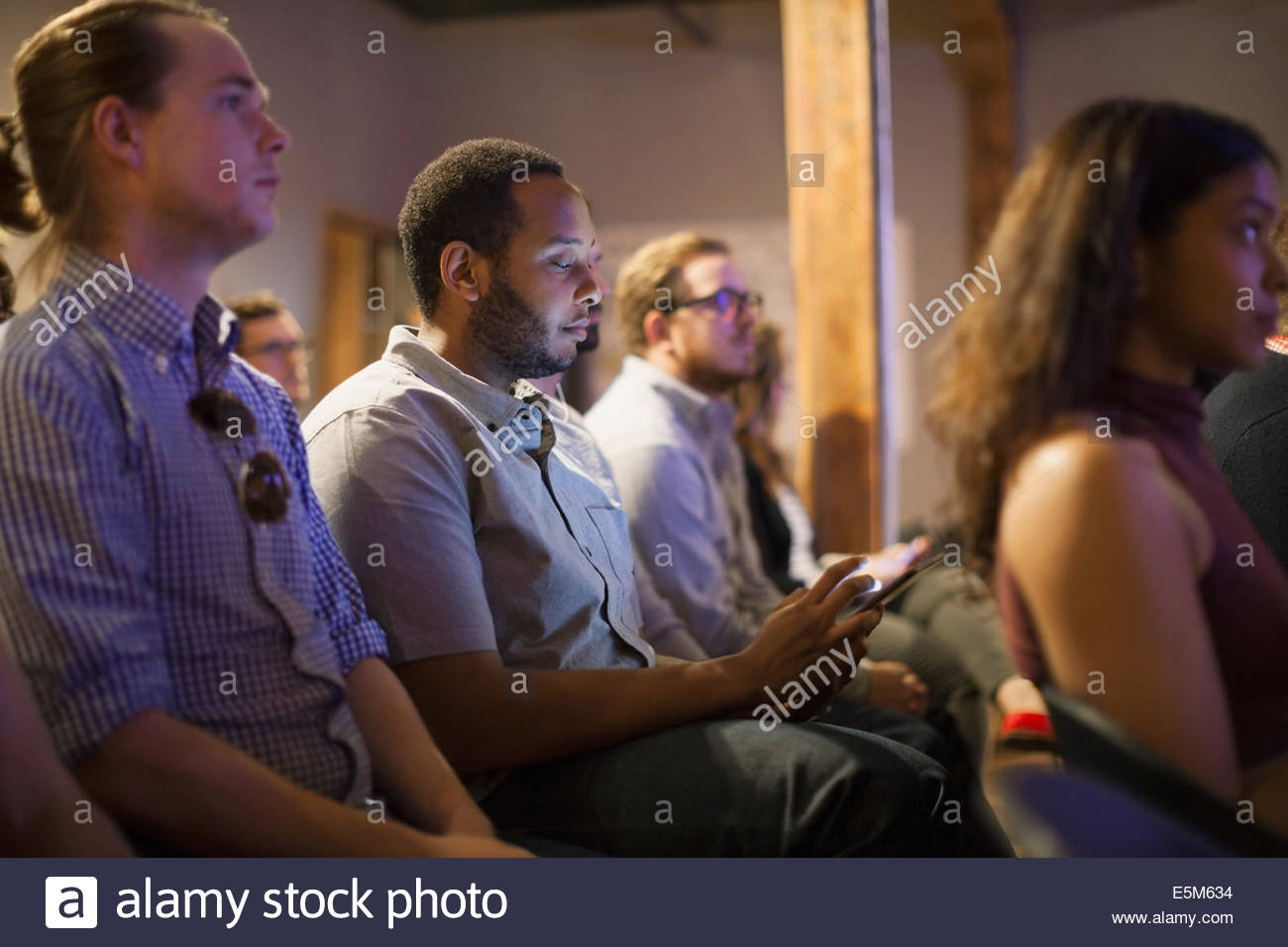 Man in audience checking cell phone Stock Photo - Alamy