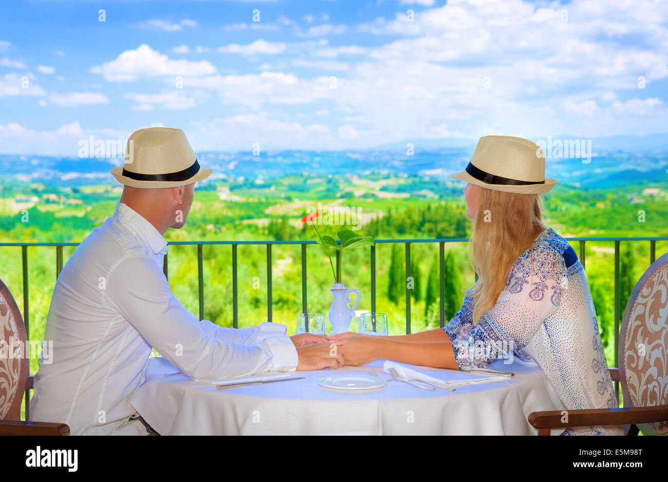 Happy couple on resort, side view of young family sitting on restaurant ...