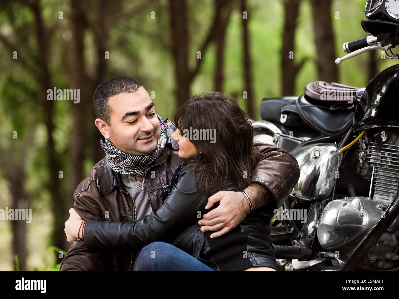 Portrait of two calm people sitting near motorcycle, looking on each ...